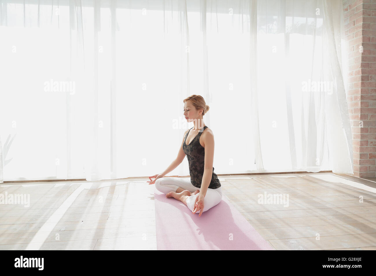 Attractive young Japanese practicing yoga in an airy room Stock Photo ...