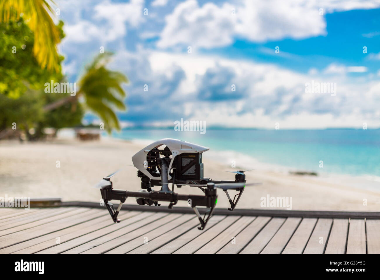 Flying drone with mounted camera at the beach. Palm trees and blue ...