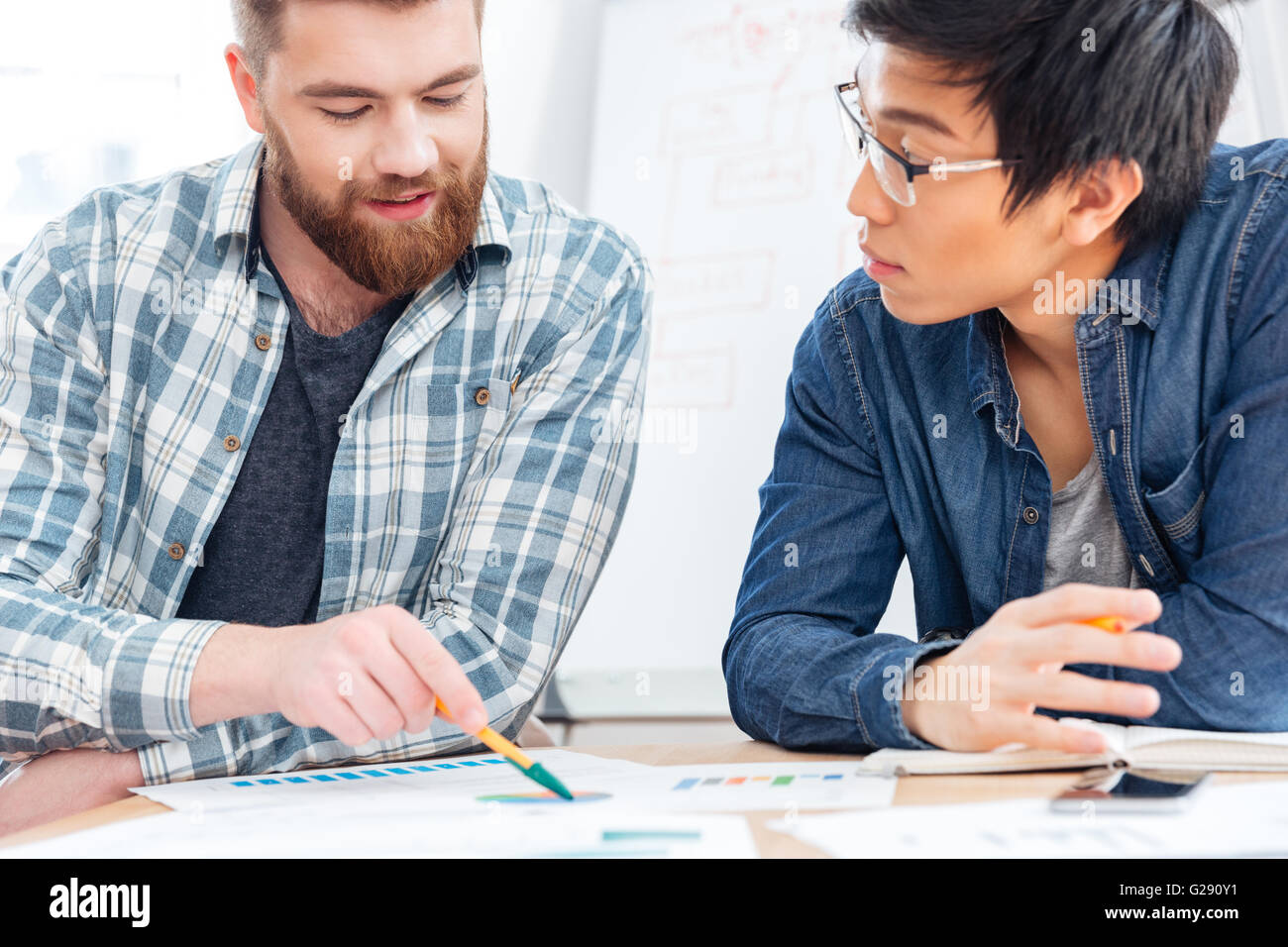 Two young businessmen discussing business plan in office Stock Photo ...