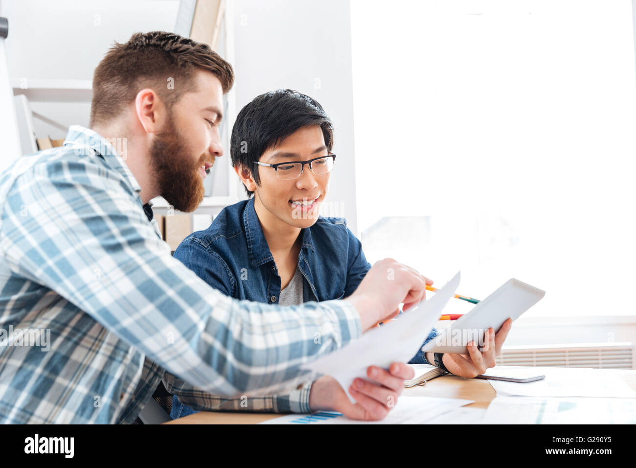 Two young businessmen making business plan and using tablet together ...