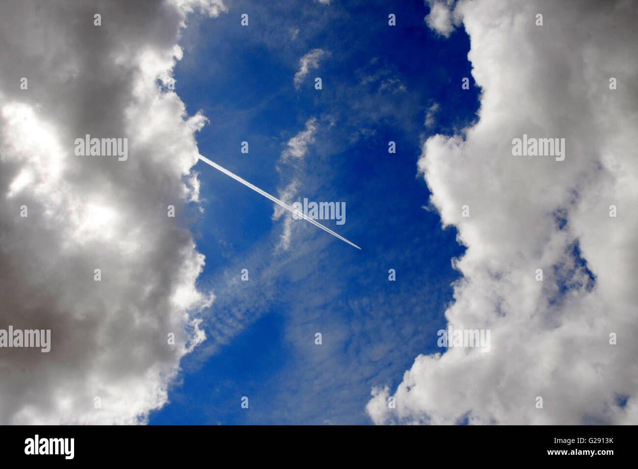 Passenger jet vapour trails between two clouds Stock Photo - Alamy