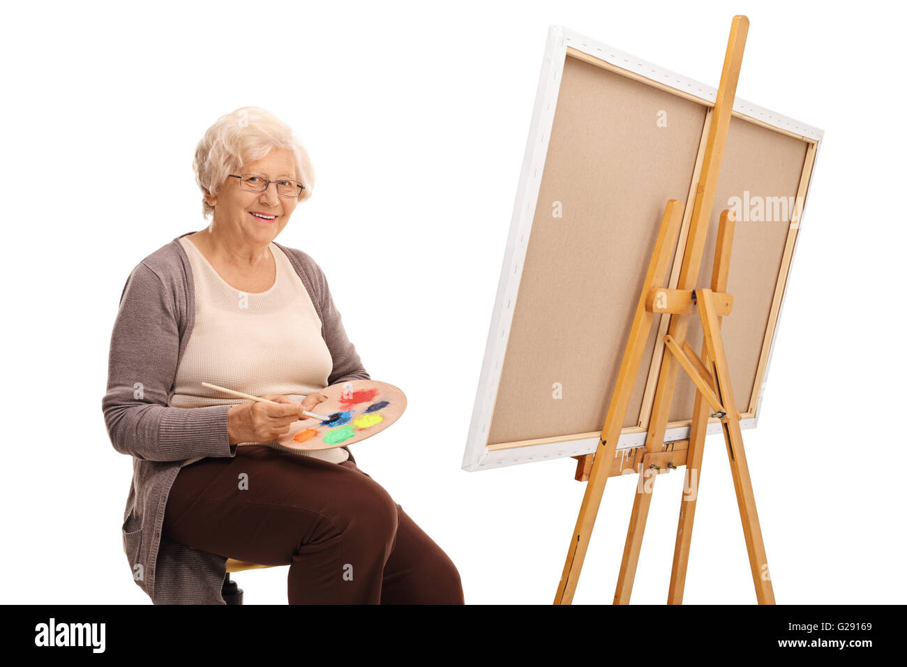 Mature woman mixing colors on a color palette and posing next to a ...