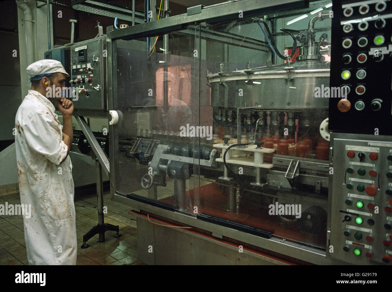 food factory worker inspecting food automated machine filling jars ...