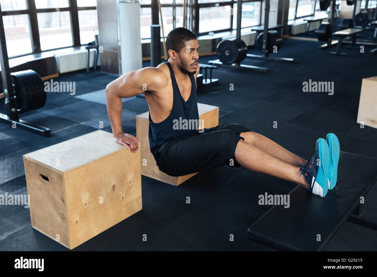Strong fitness man pumps biceps using training apparatus in the gym ...