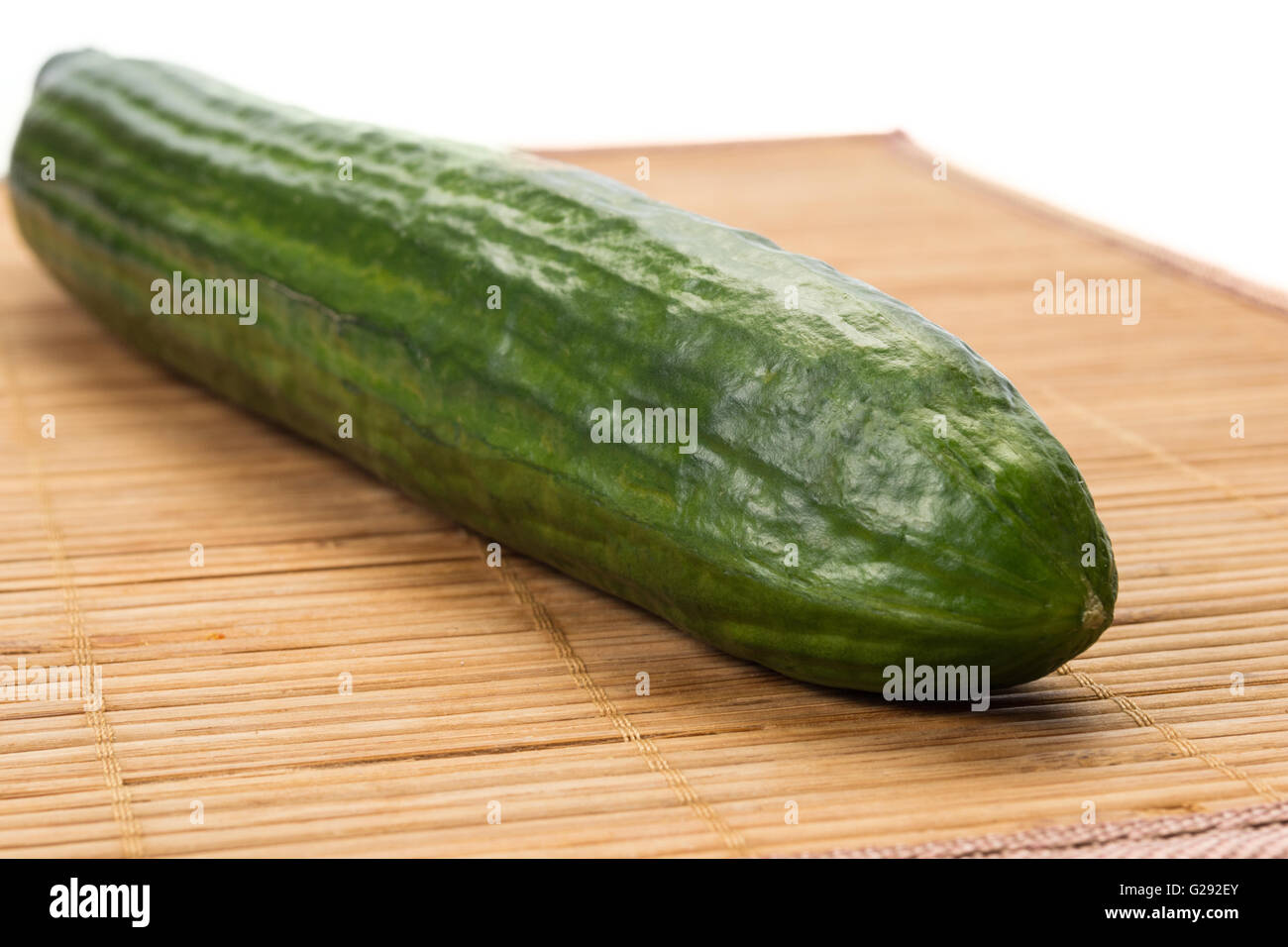 One fresh big green cucumber sitting on a bamboo table with white ...
