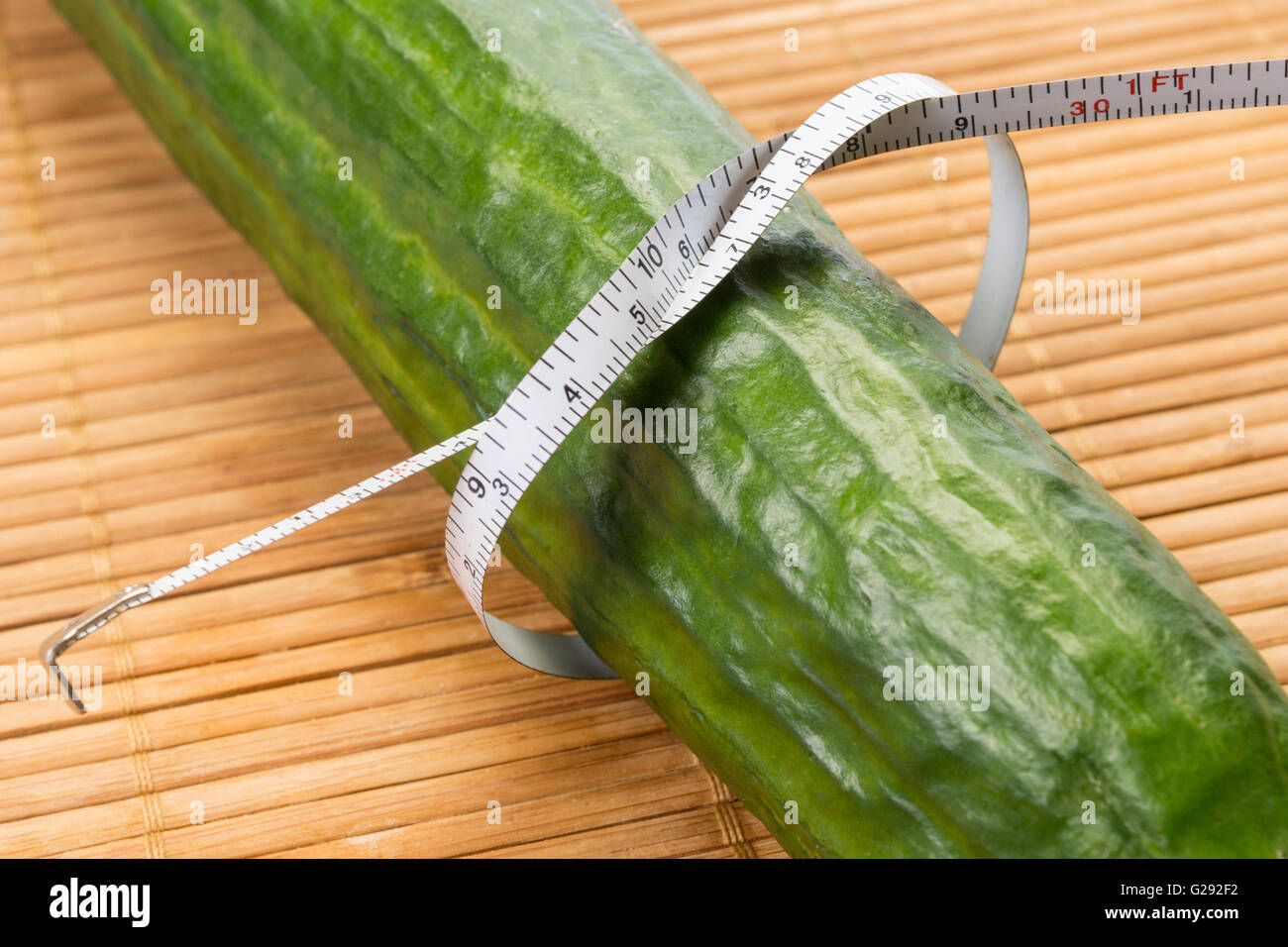 Closeup with a white centimetter measuring a big green cucumber on a ...