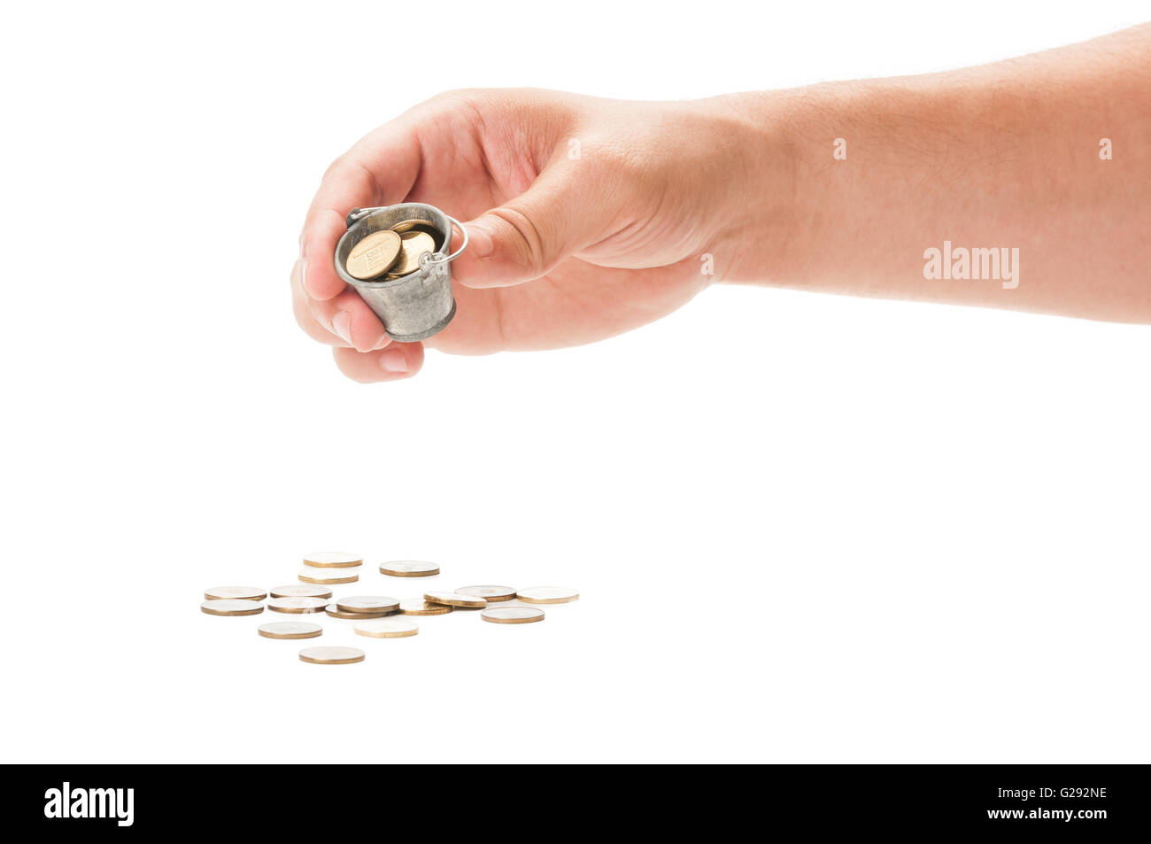 Hand pouring a bucket of coins on a white table with white background ...