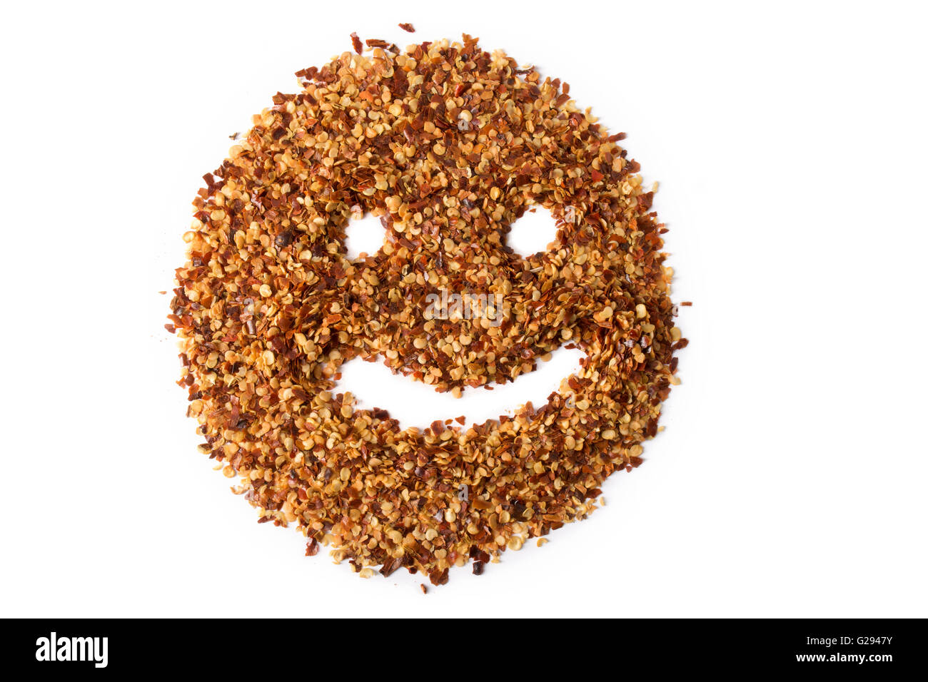 A pile of crushed red pepper flakes showing a smiley face, depicting ...