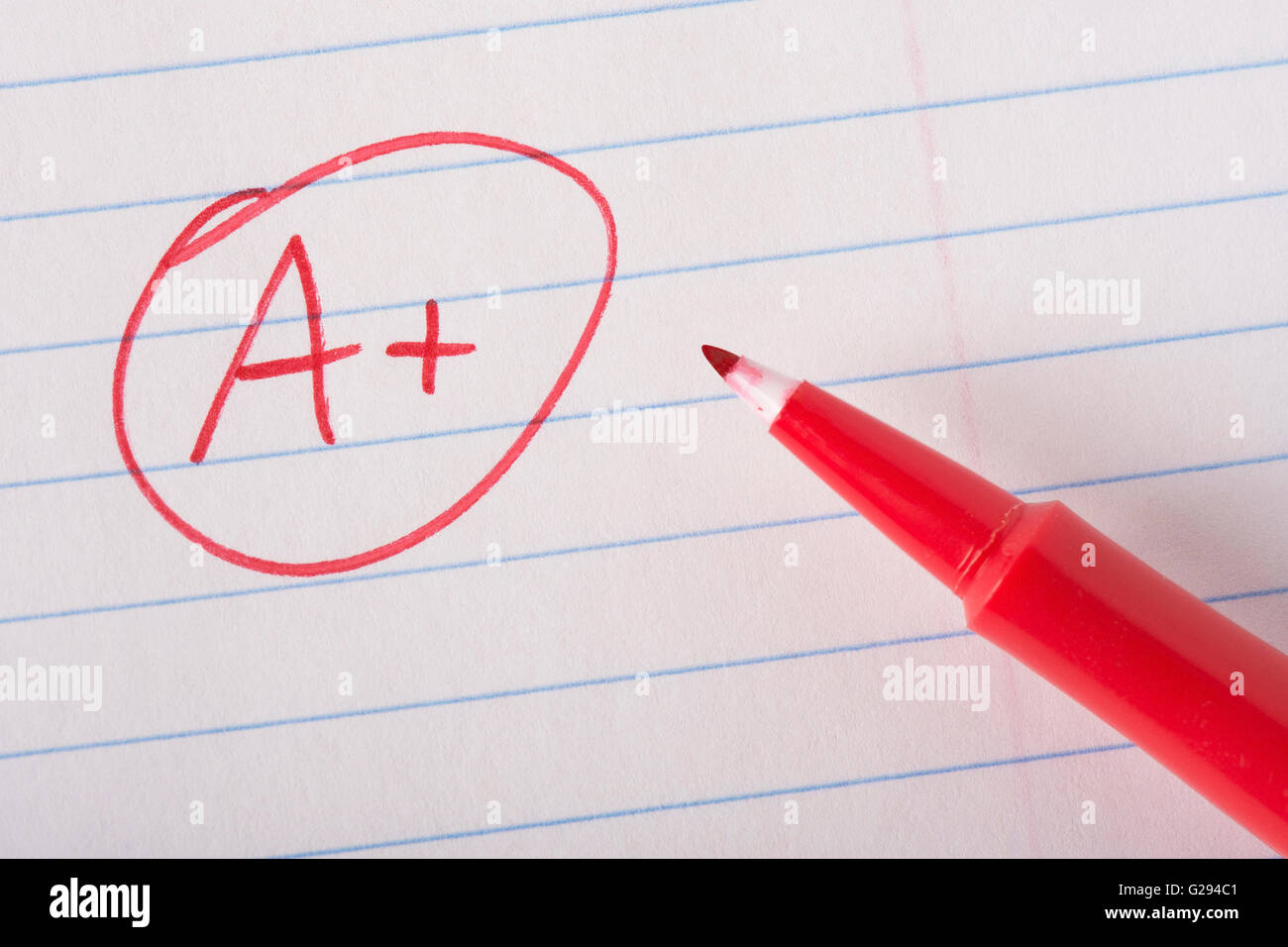 A plus (A+) grade written in red pen on notebook paper with the pen ...
