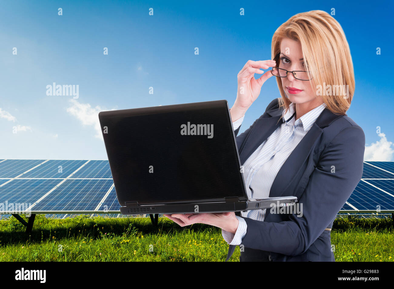 Businesswoman with solar power plant in background holding laptop ...