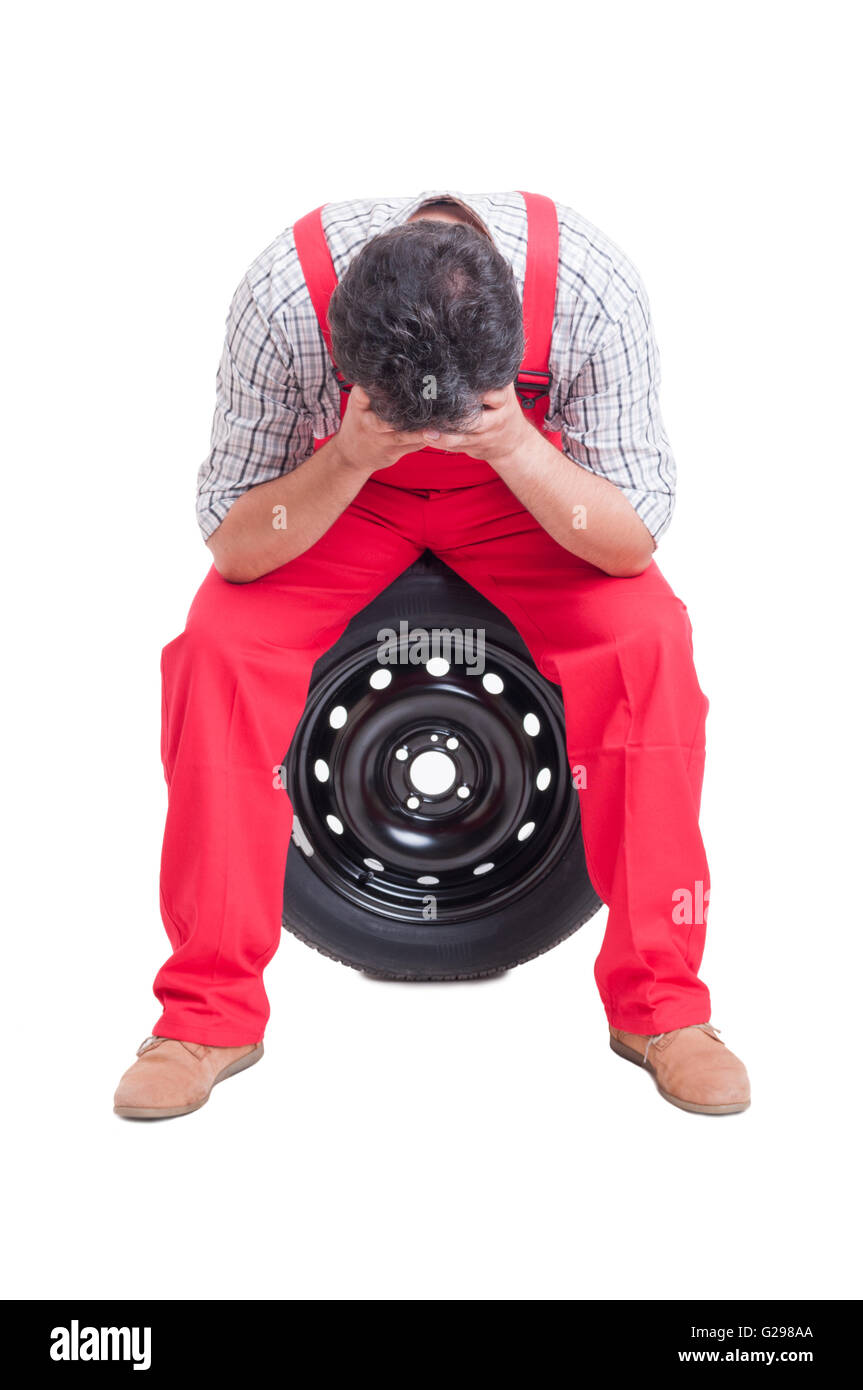 Stressed mechanic resting head in hands and sitting on a tire Stock ...