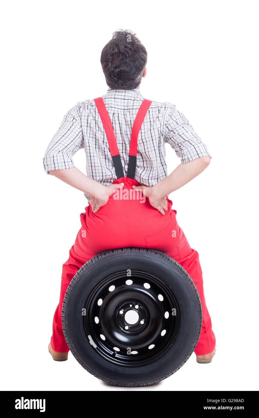 Mechanic suffering of lower back or lumbar area pain sitting on a tire ...