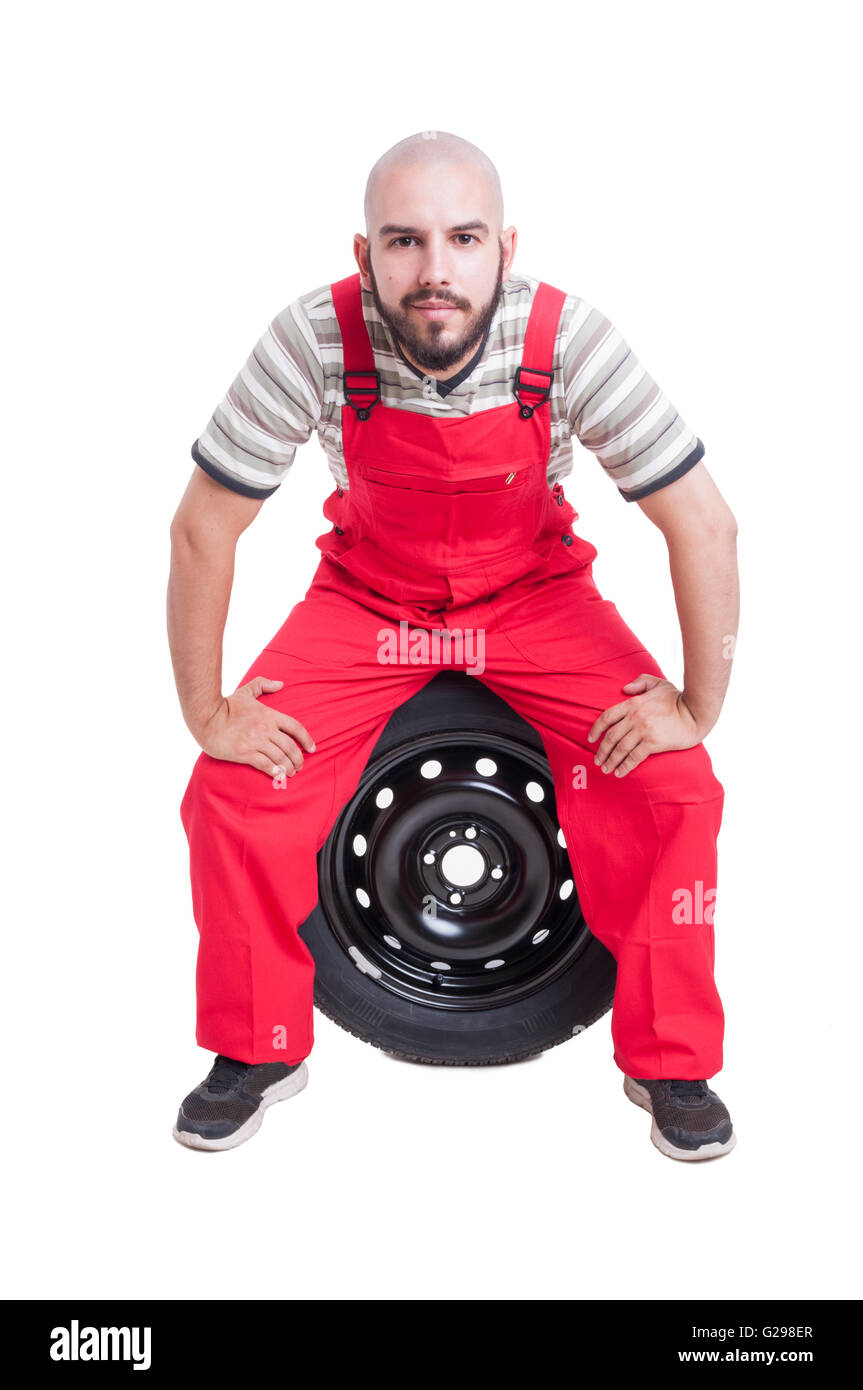 Friendly mechanic sitting on car wheel isolated on white studio ...
