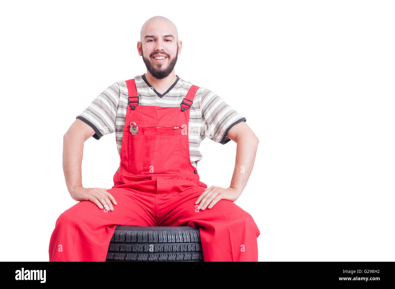 Happy smiling mechanic sitting on stack of car wheels isolated on white ...