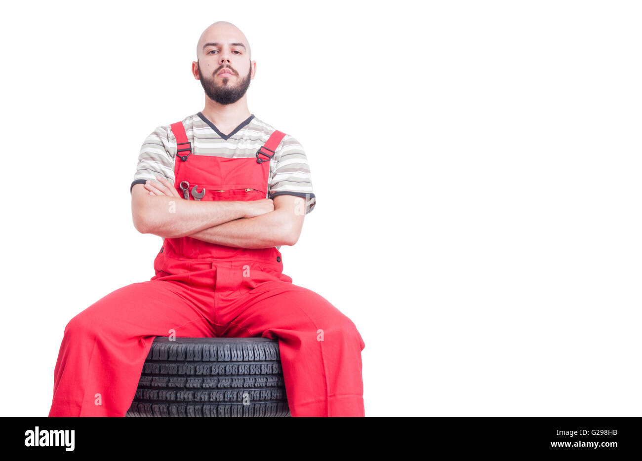 Proud mechanic sitting on top of car wheels with arms crossed looking ...