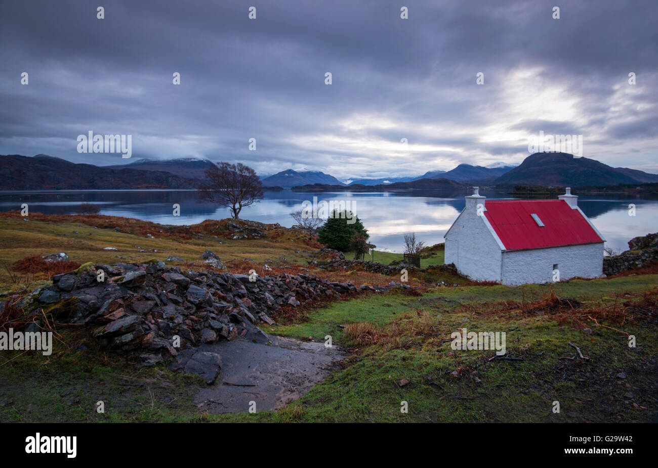 White cottage with a red roof, on the banks of Loch Shieldaig at ...