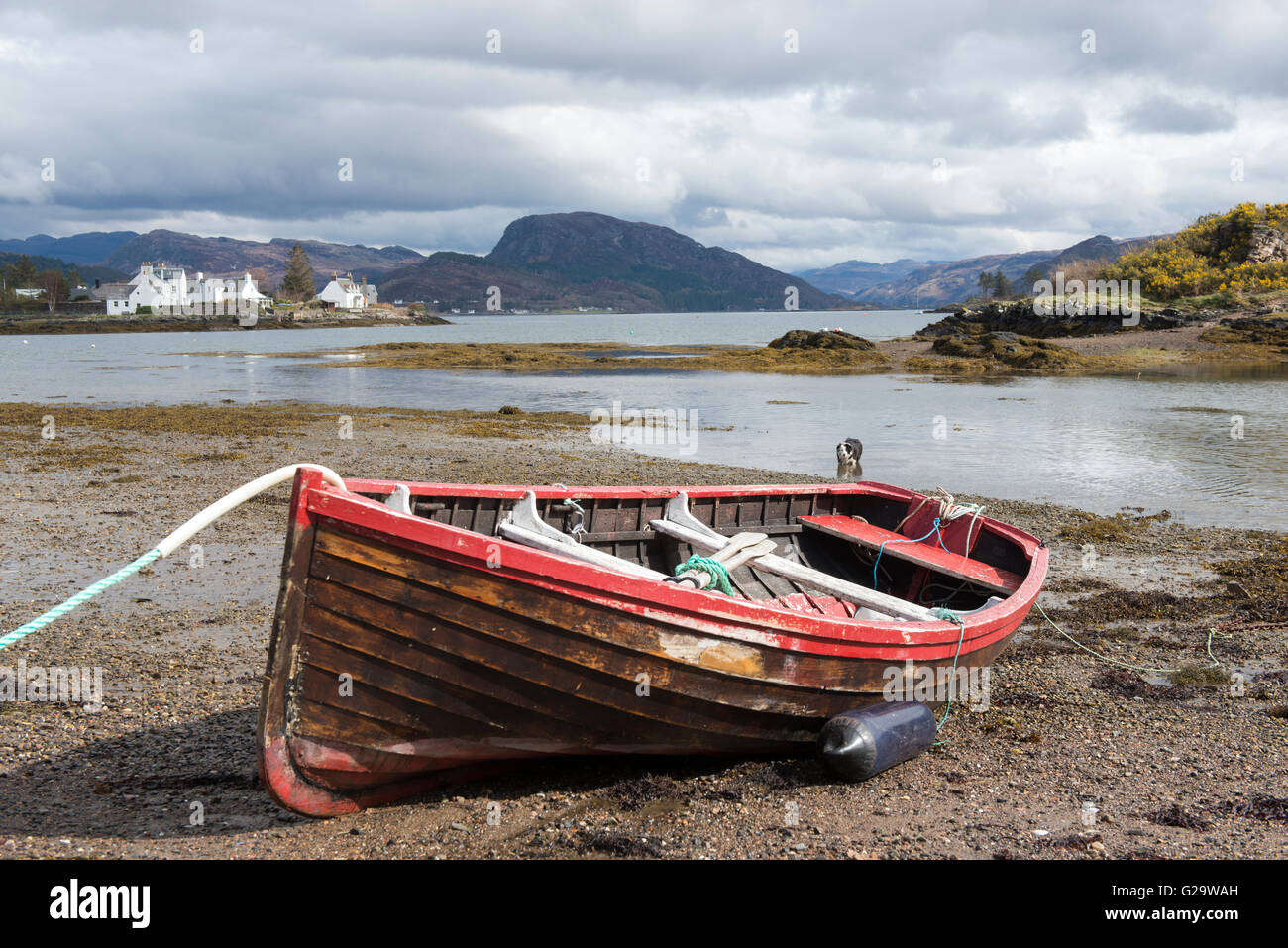 A weathered red boat on the beach in the village of Plockton, Ross ...