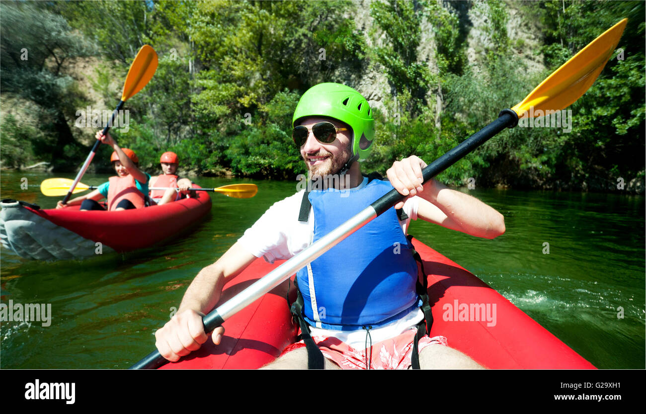 A male in red inflatable canoe having fun in calm waters of a river ...