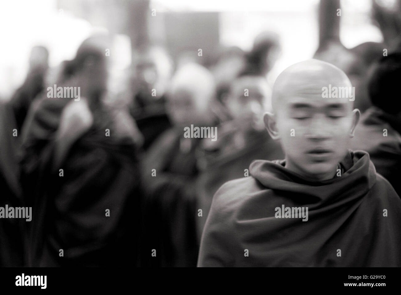 A Tibetan monk finds a moment to meditate while standing in line to be ...