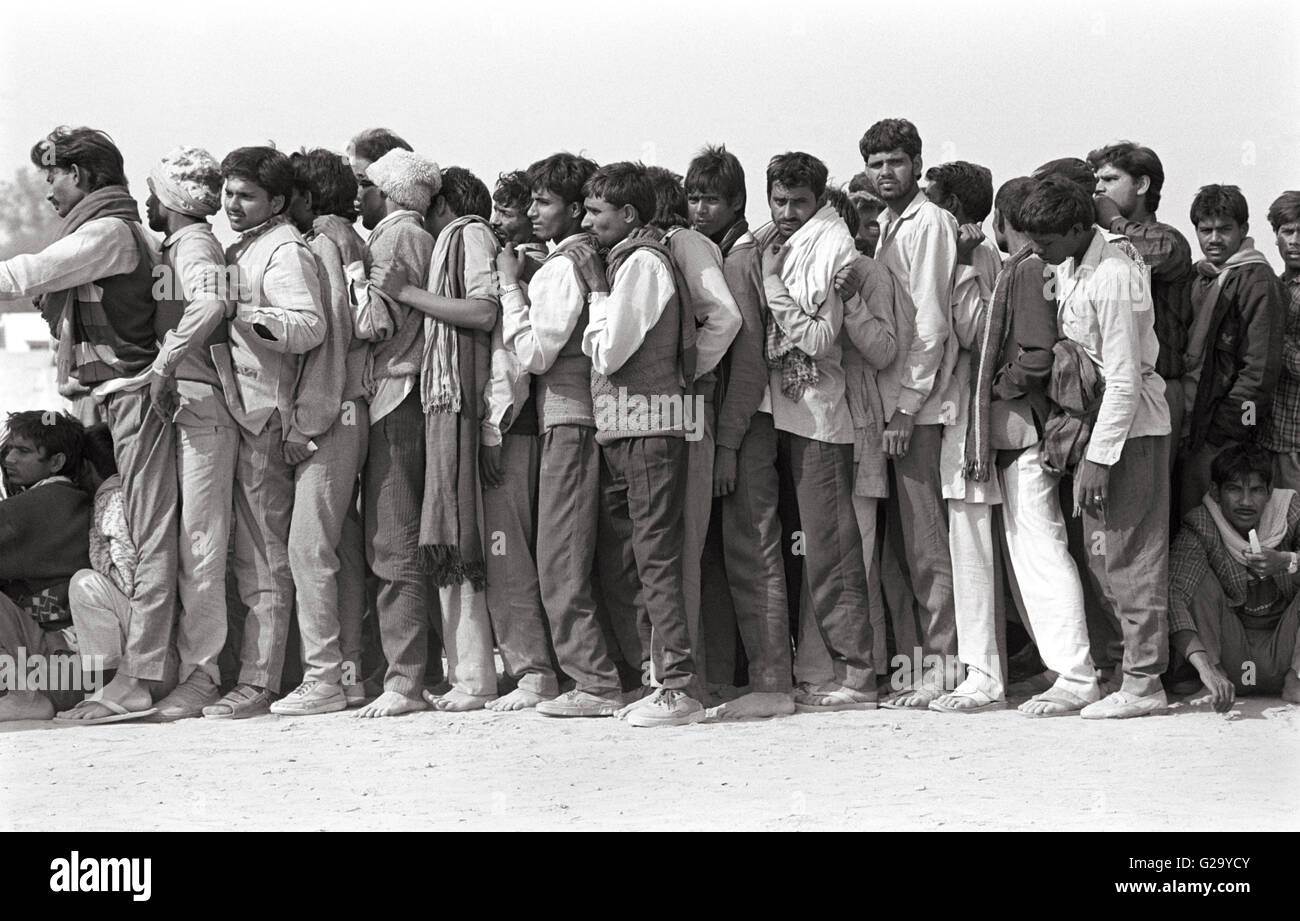 A group of Indian men line up outside a mosque construction site to ...