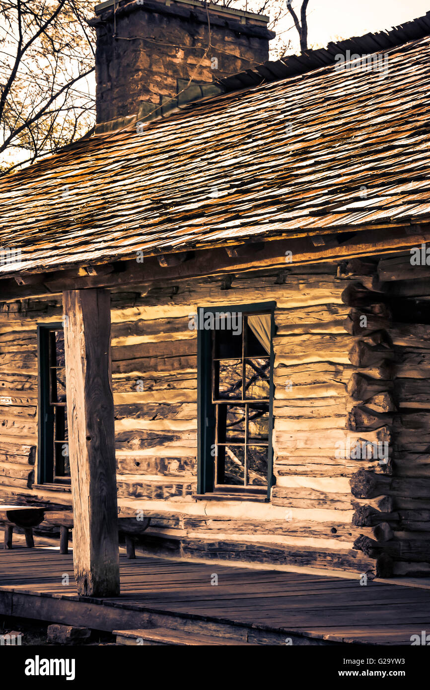 A charming rustic log cabin with front porch and seats in a 19th ...