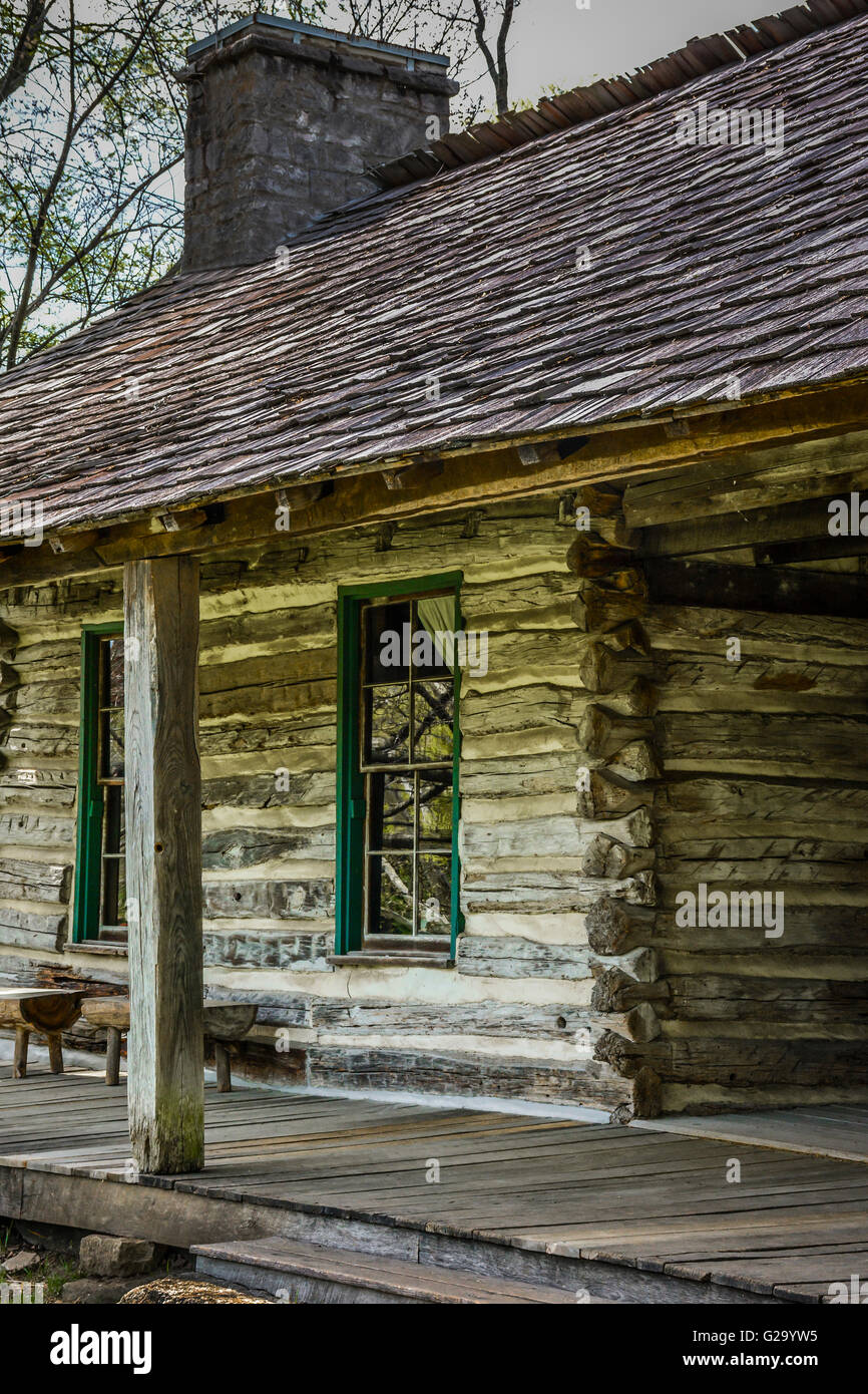 A charming rustic log cabin with front porch and seats in a 19th ...