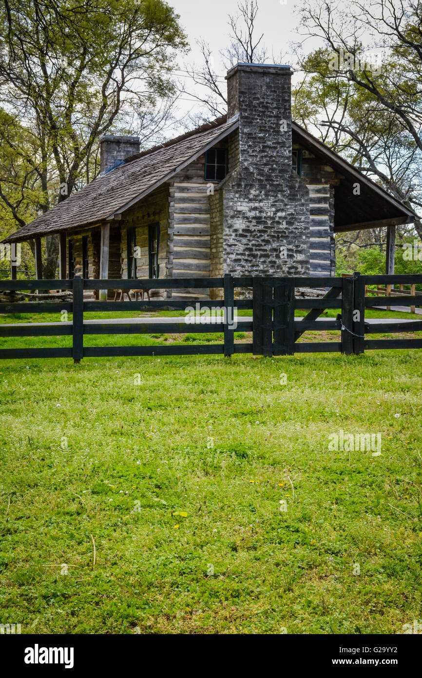 A charming rustic log cabin with front porch and seats in a 19th ...
