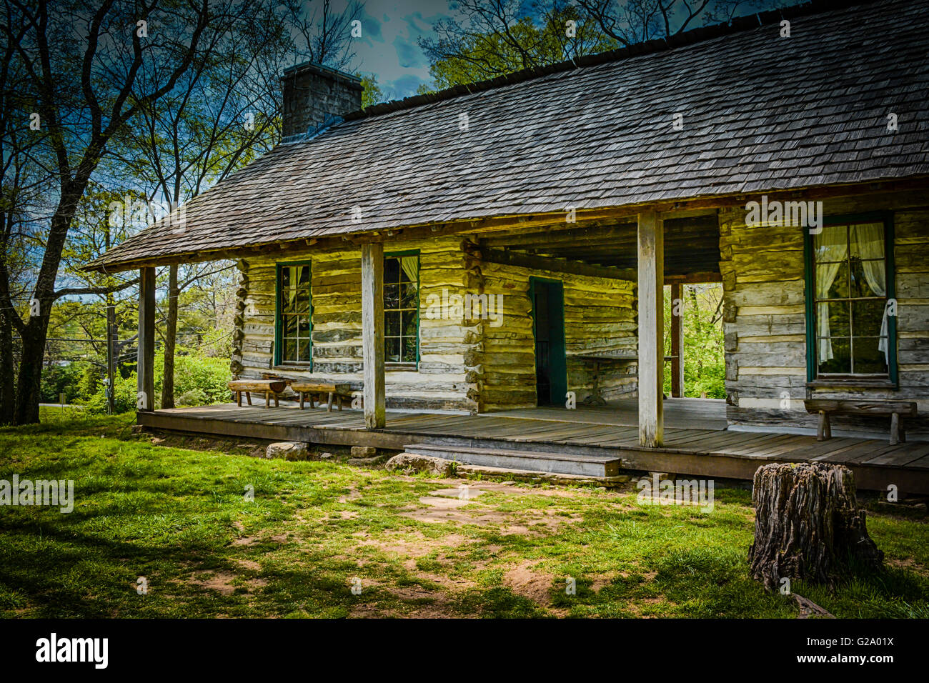 A charming rustic log cabin with front porch and benches in a 19th ...