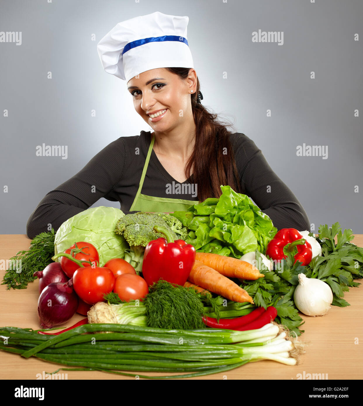 Woman cook with various vegetables in front of her on a wooden board ...