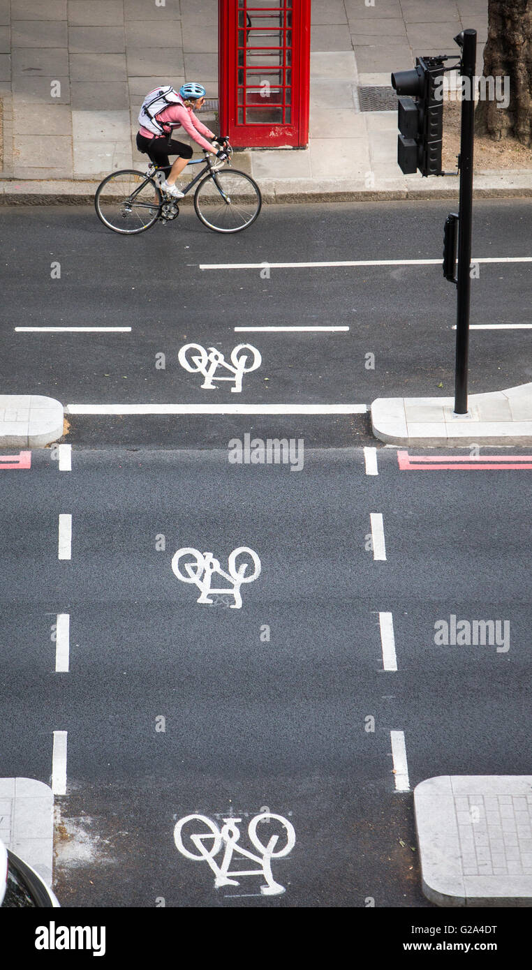 An aerial view of a cyclist in a cycle lane passing a red phone box ...