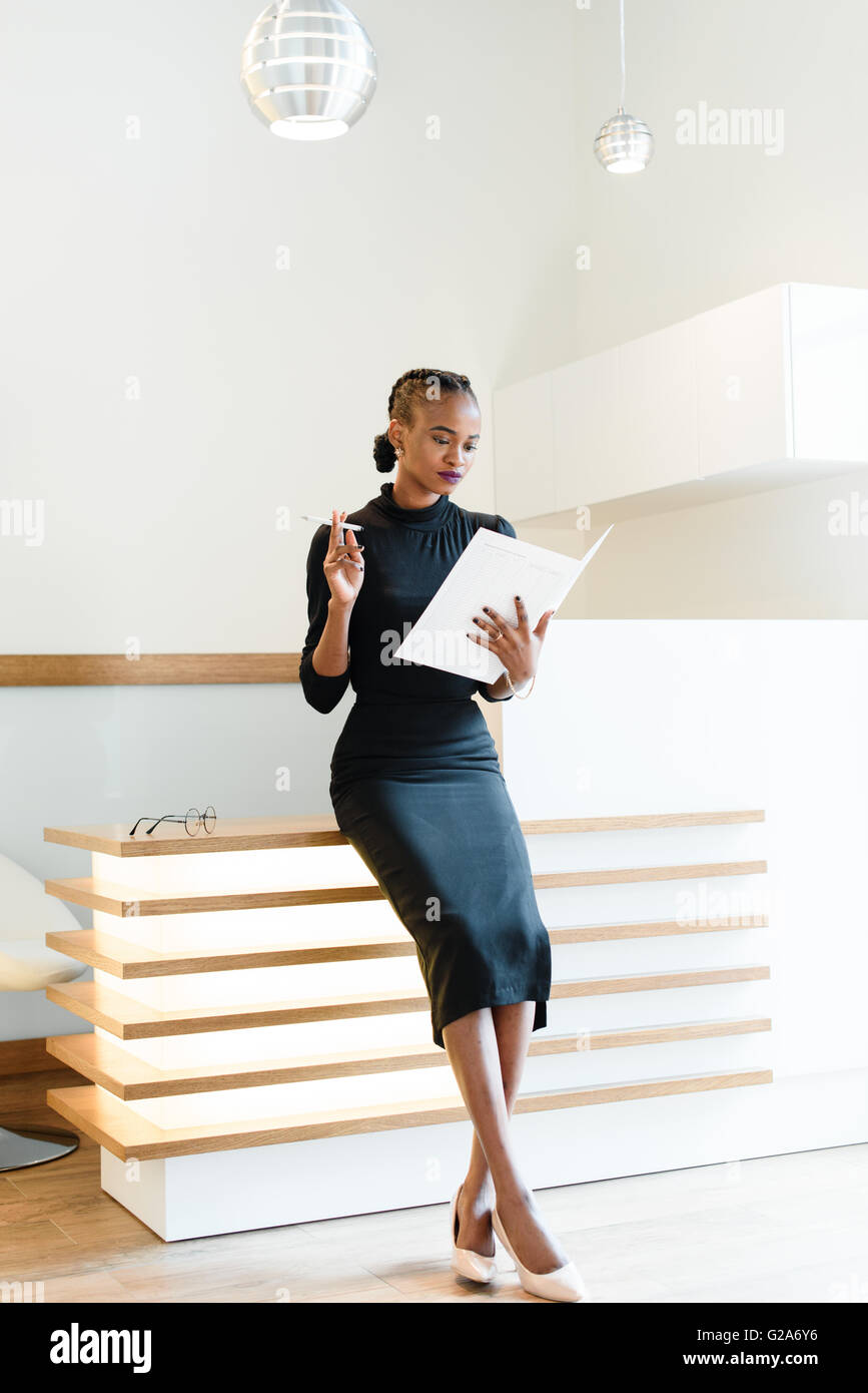 Stern elegant business woman wearing black dress and beige shoes in ...