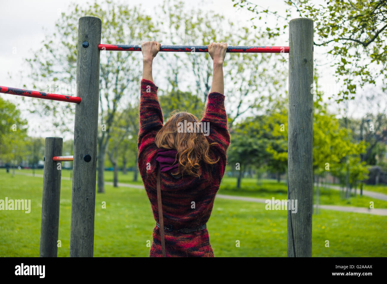 A young woman is doing pull ups in a park Stock Photo - Alamy