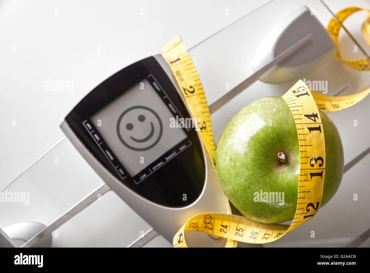 Scale with happy face message, apple and tape measure on white table ...