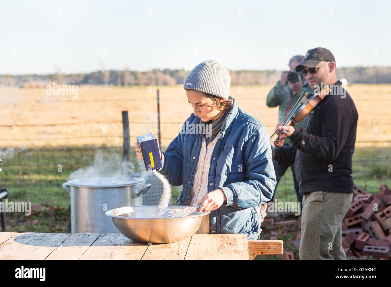 A fiddler plays as volunteers prepare for a hog slaughter during a ...