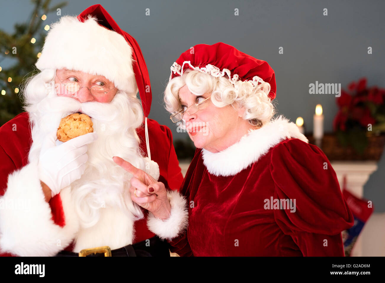 Mrs. Claus pointing on Santa eating gingerbread cookie Stock Photo - Alamy