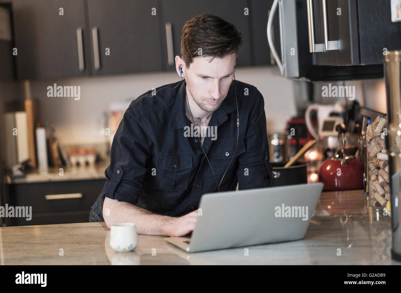 Man working on laptop computer in kitchen Stock Photo - Alamy
