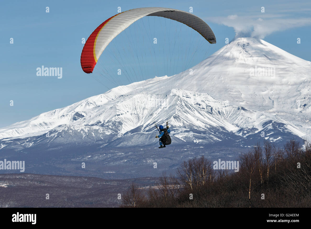 Paraglider flying on the background of the active volcano Stock Photo ...