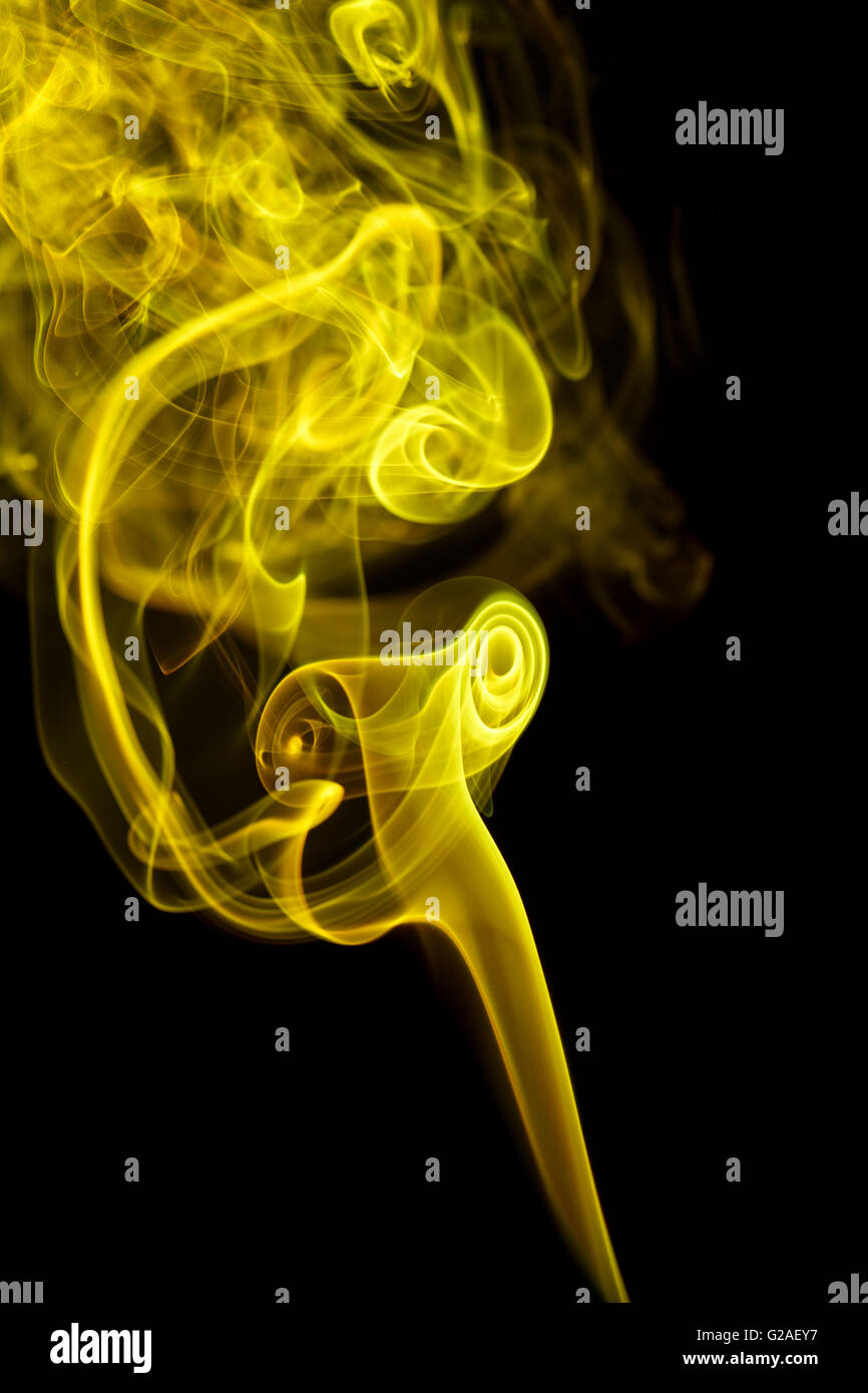 Abstract art. Color yellow smoke from the aromatic sticks on a black ...