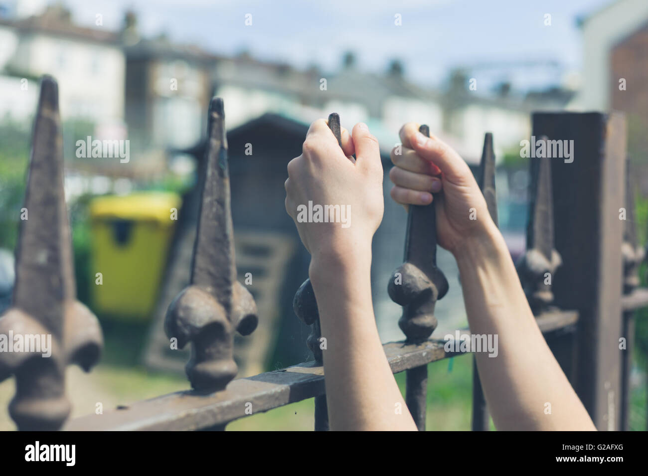 Close up on a woman's hands as she is holding onto a fence outside a ...
