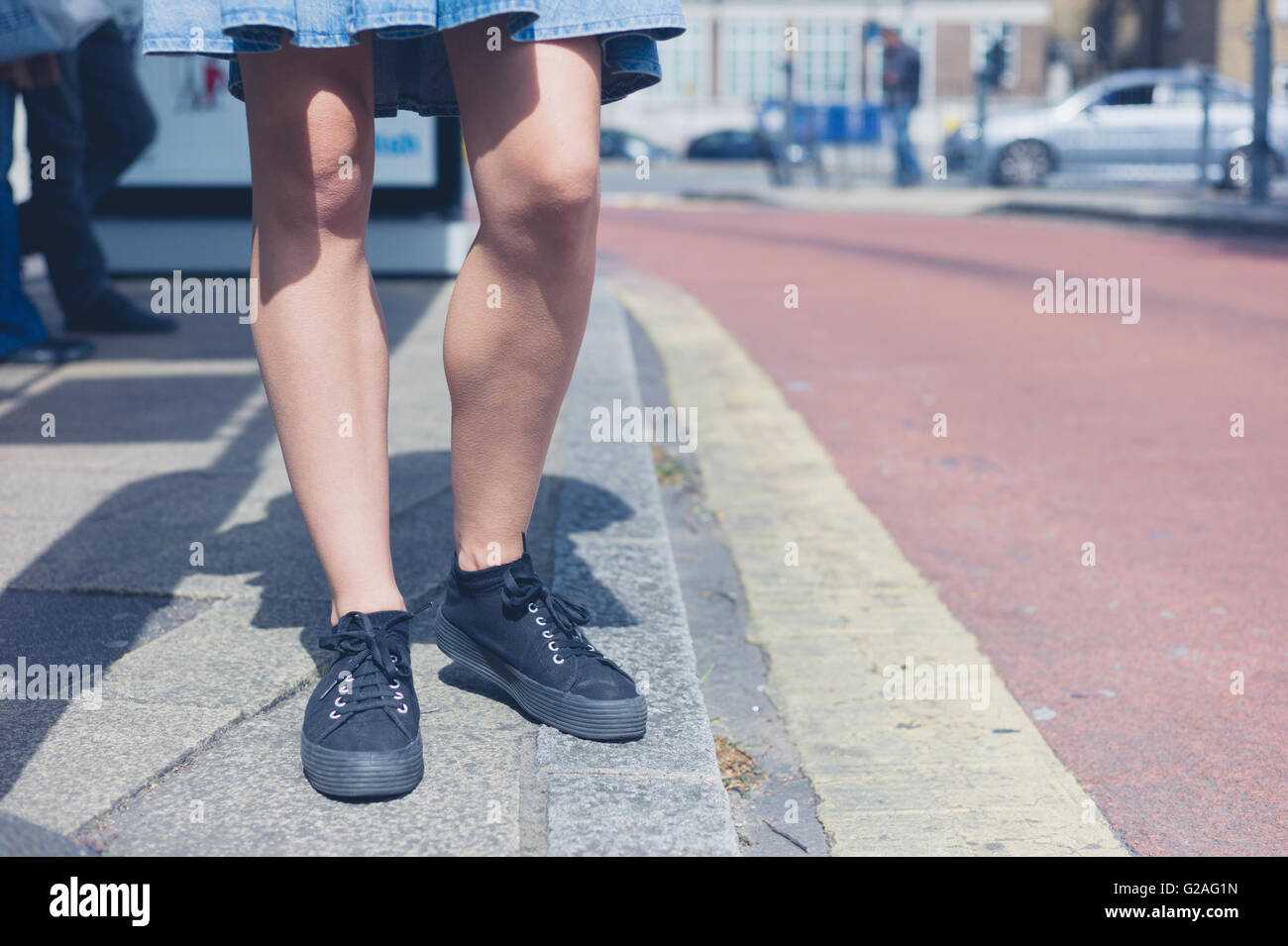 The legs of a young woman as she is waiting at a bus stop Stock Photo ...