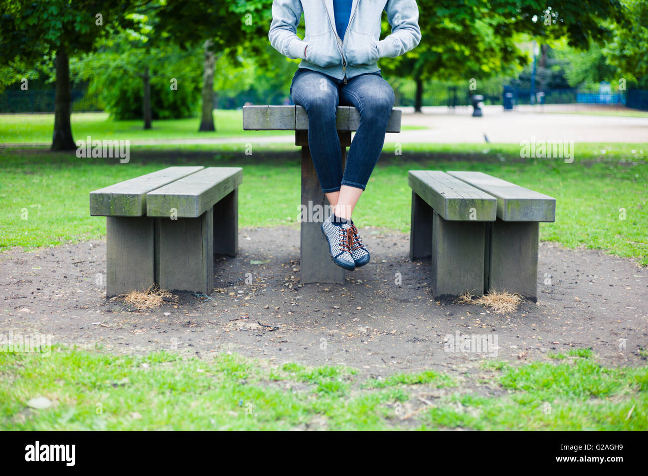 A young woman is sitting on a table in a park Stock Photo - Alamy