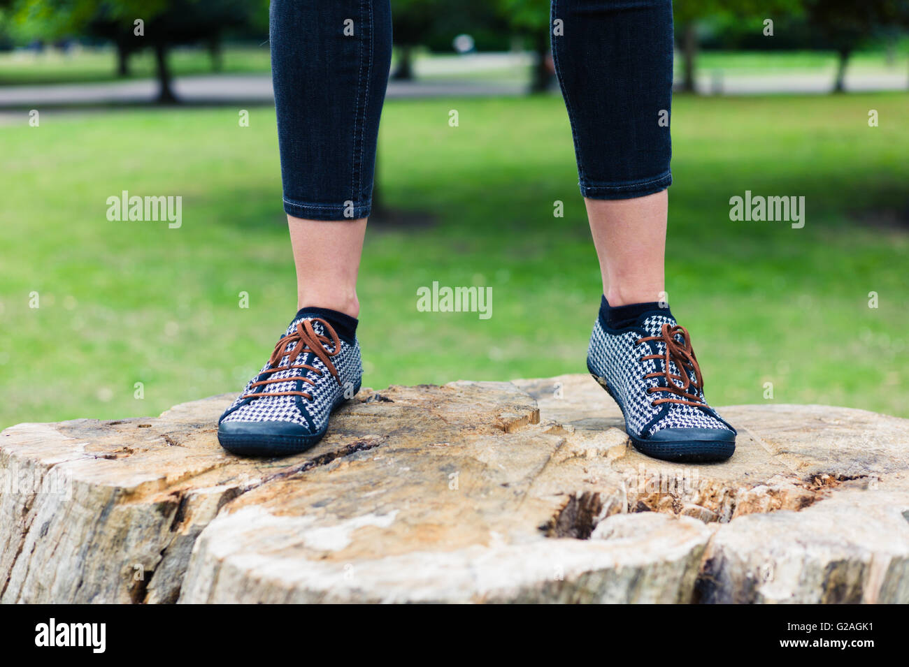 The feet of a trendy young woman standing on a tree trunk Stock Photo ...