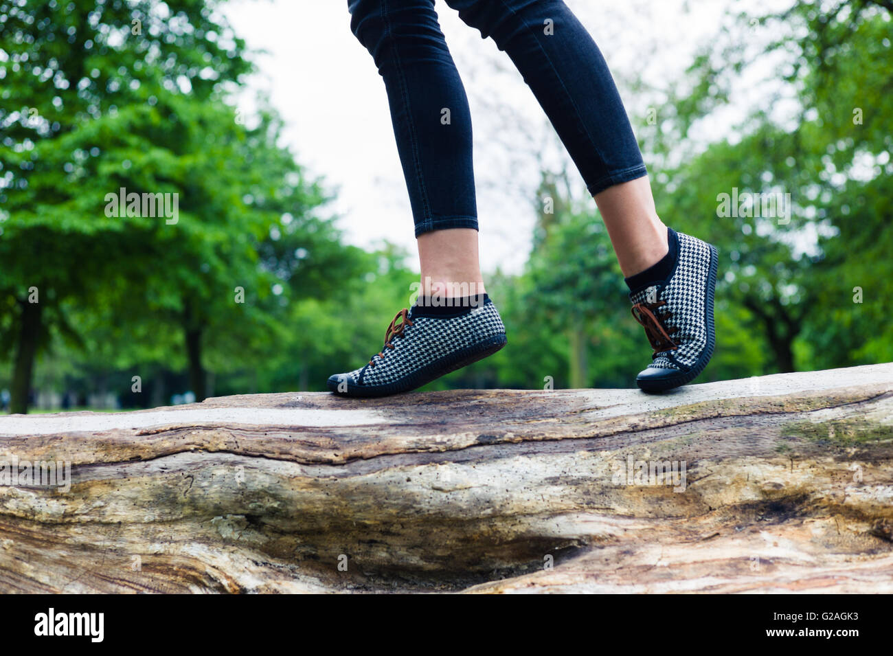 The feet of a trendy young woman as she is walking on a tree trunk in ...