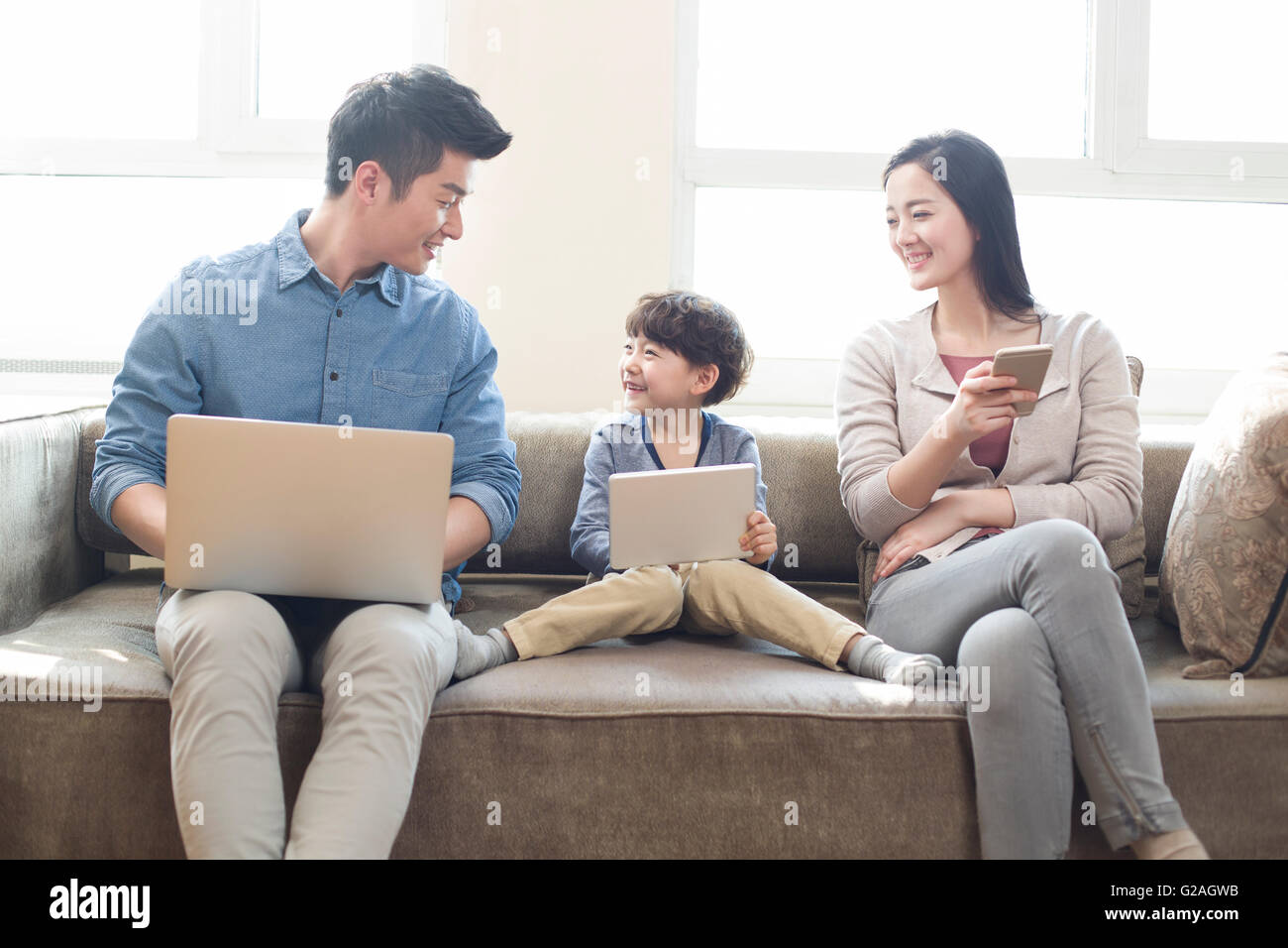 Happy young family using laptop and digital tablet Stock Photo - Alamy