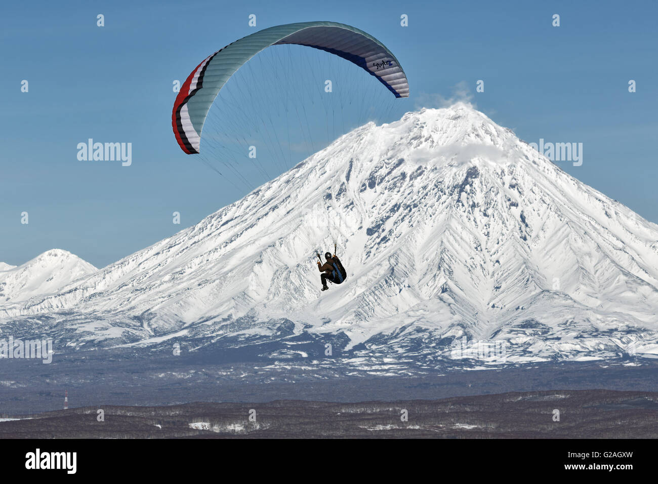 Paraglider flying on the background of the active Koriaksky Volcano ...
