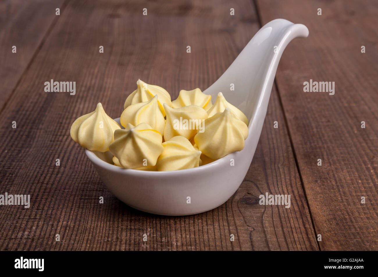 Yellow sweets in cup on wood table Stock Photo - Alamy