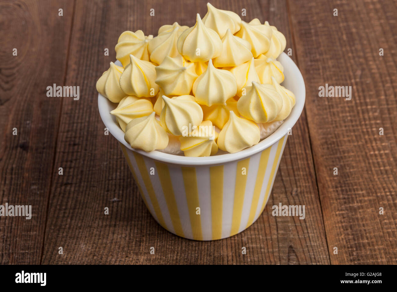 Yellow sweets in cup on wood table Stock Photo - Alamy