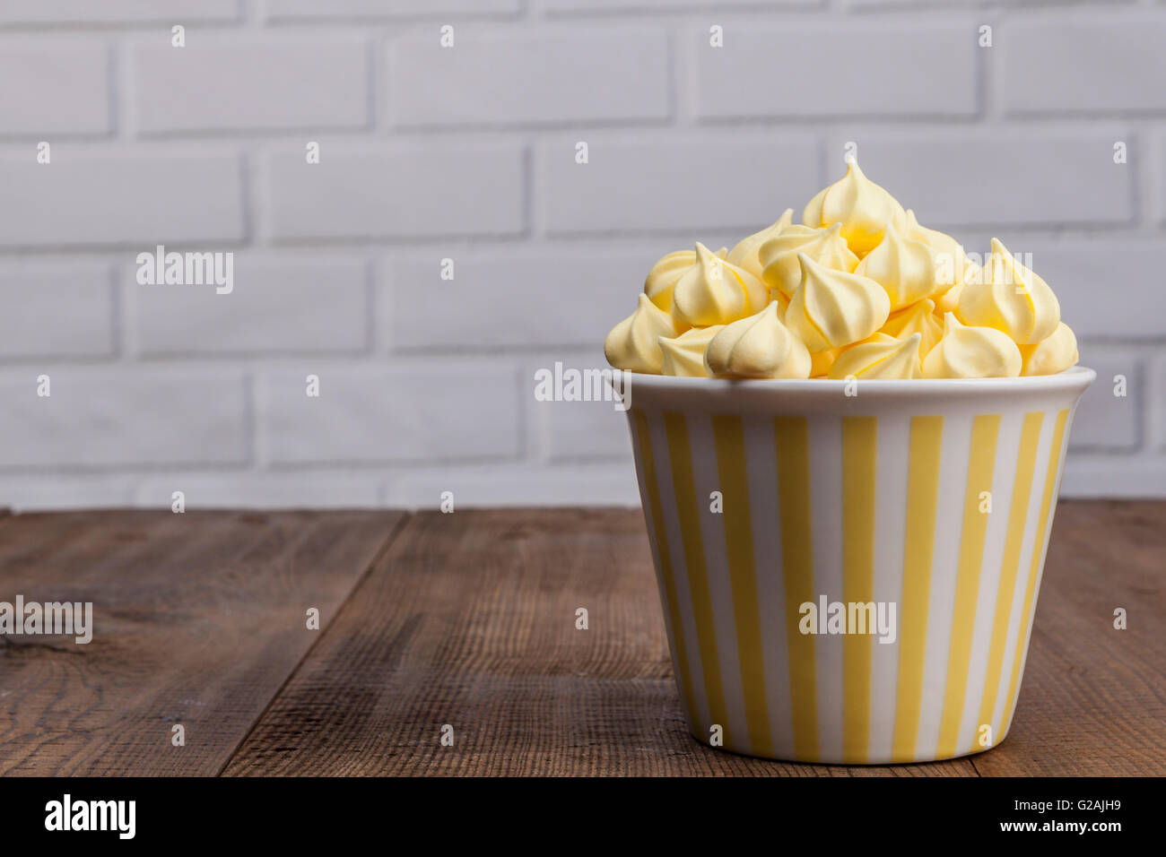 Yellow Sweets on wood table and white brick background Stock Photo - Alamy