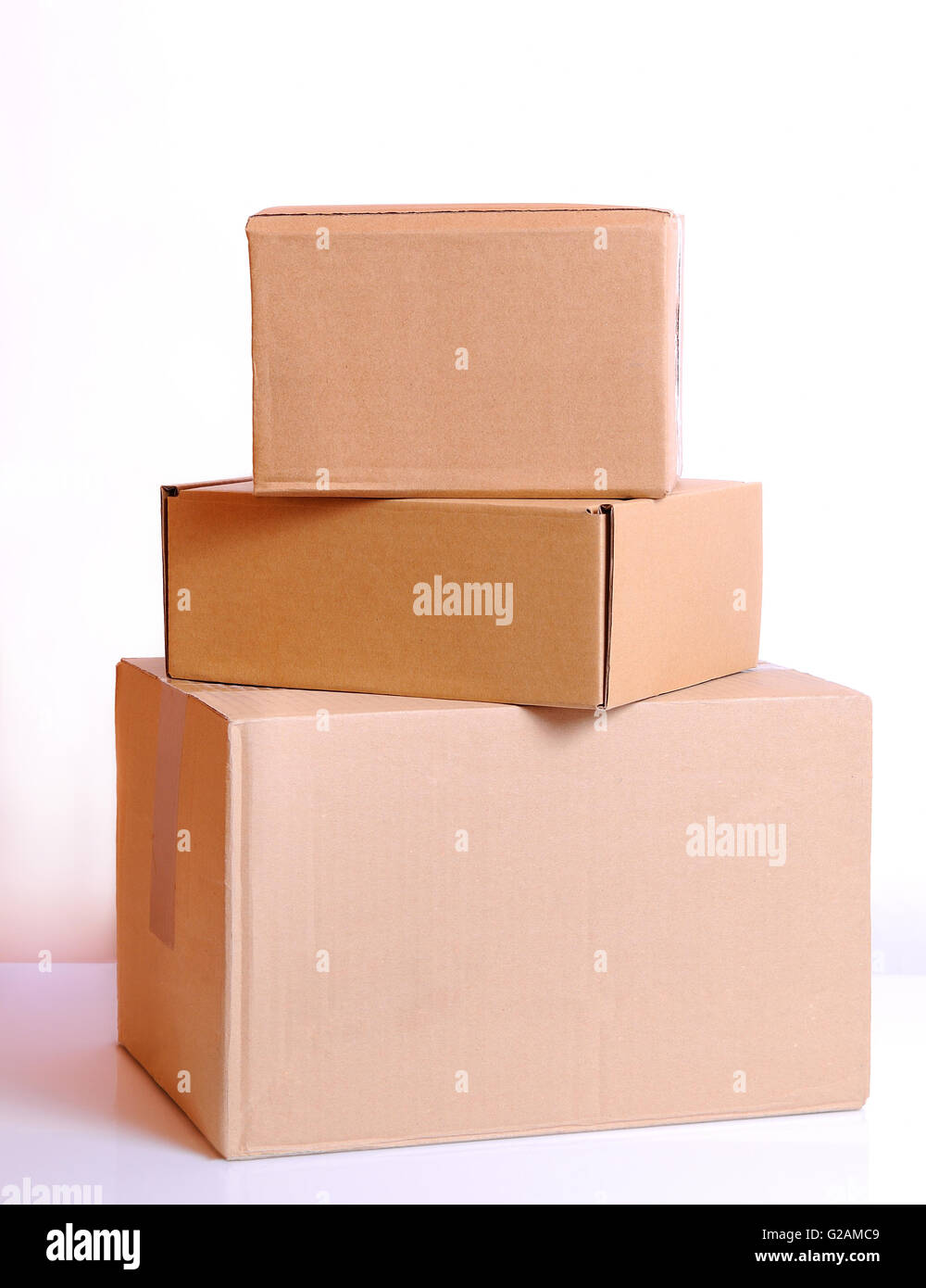 Three brown cardboard boxes isolated over white table Stock Photo - Alamy