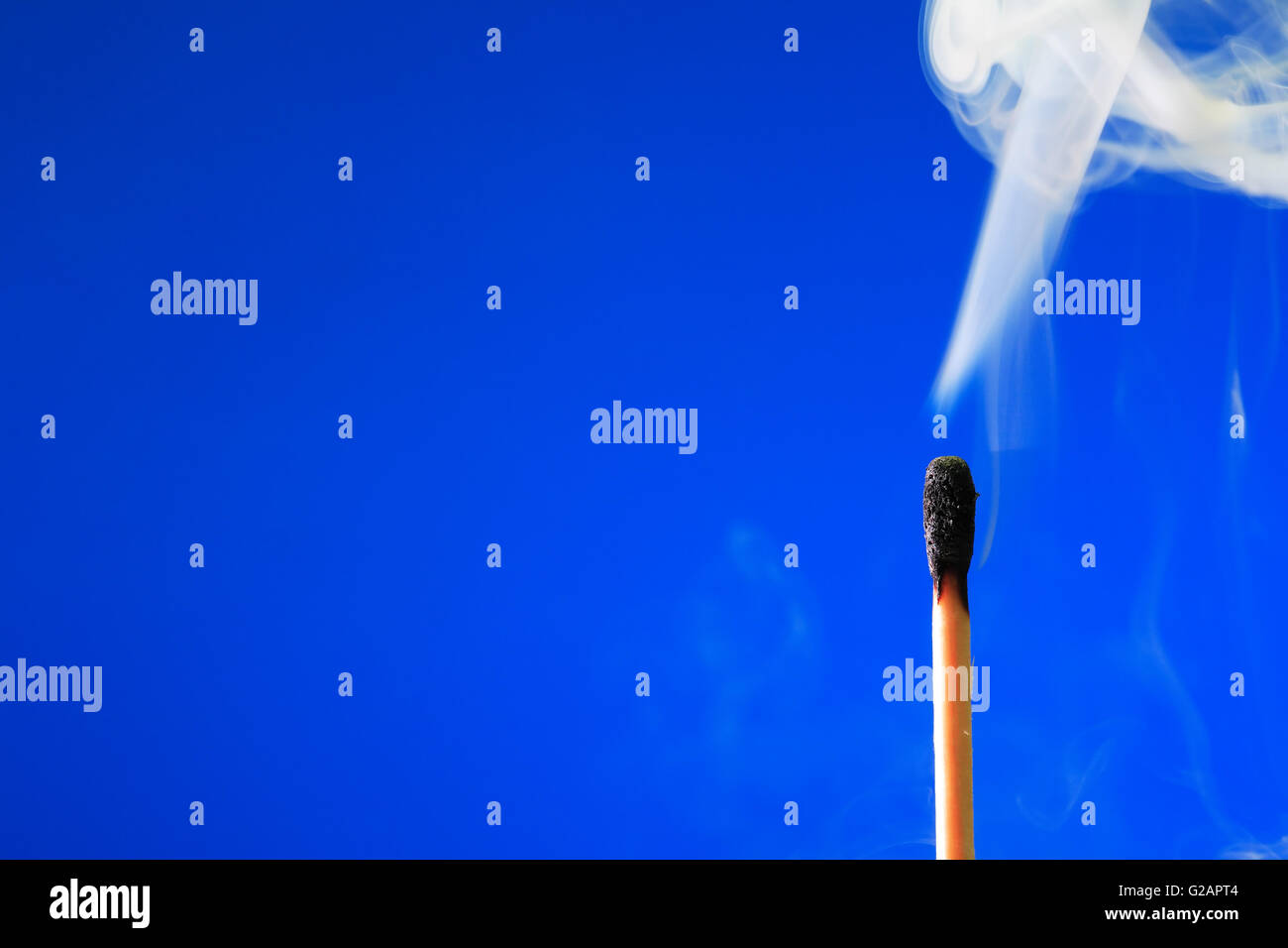 Extinguished match with smoke on blue background Stock Photo - Alamy